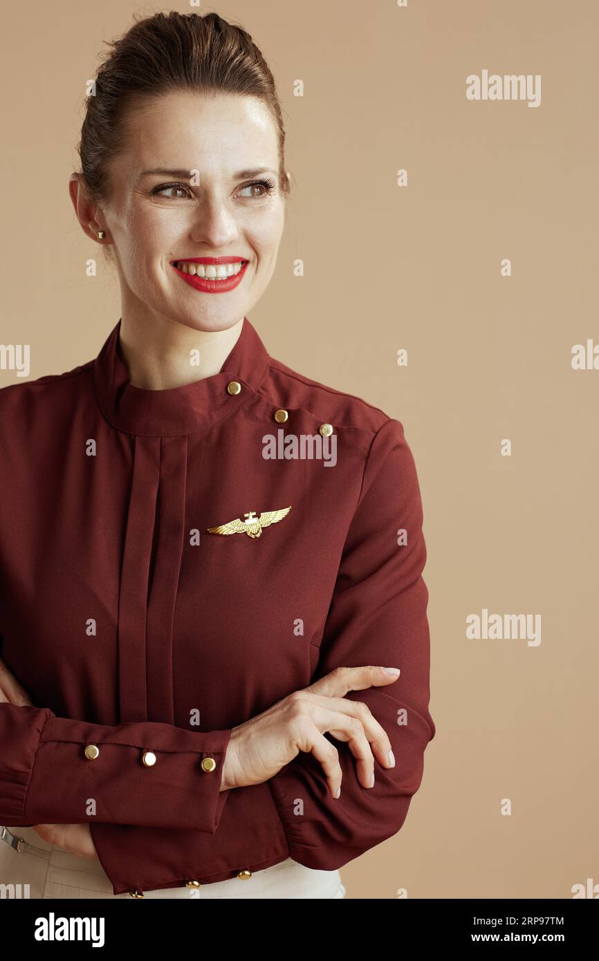 happy modern air hostess woman against beige background looking at copy ...