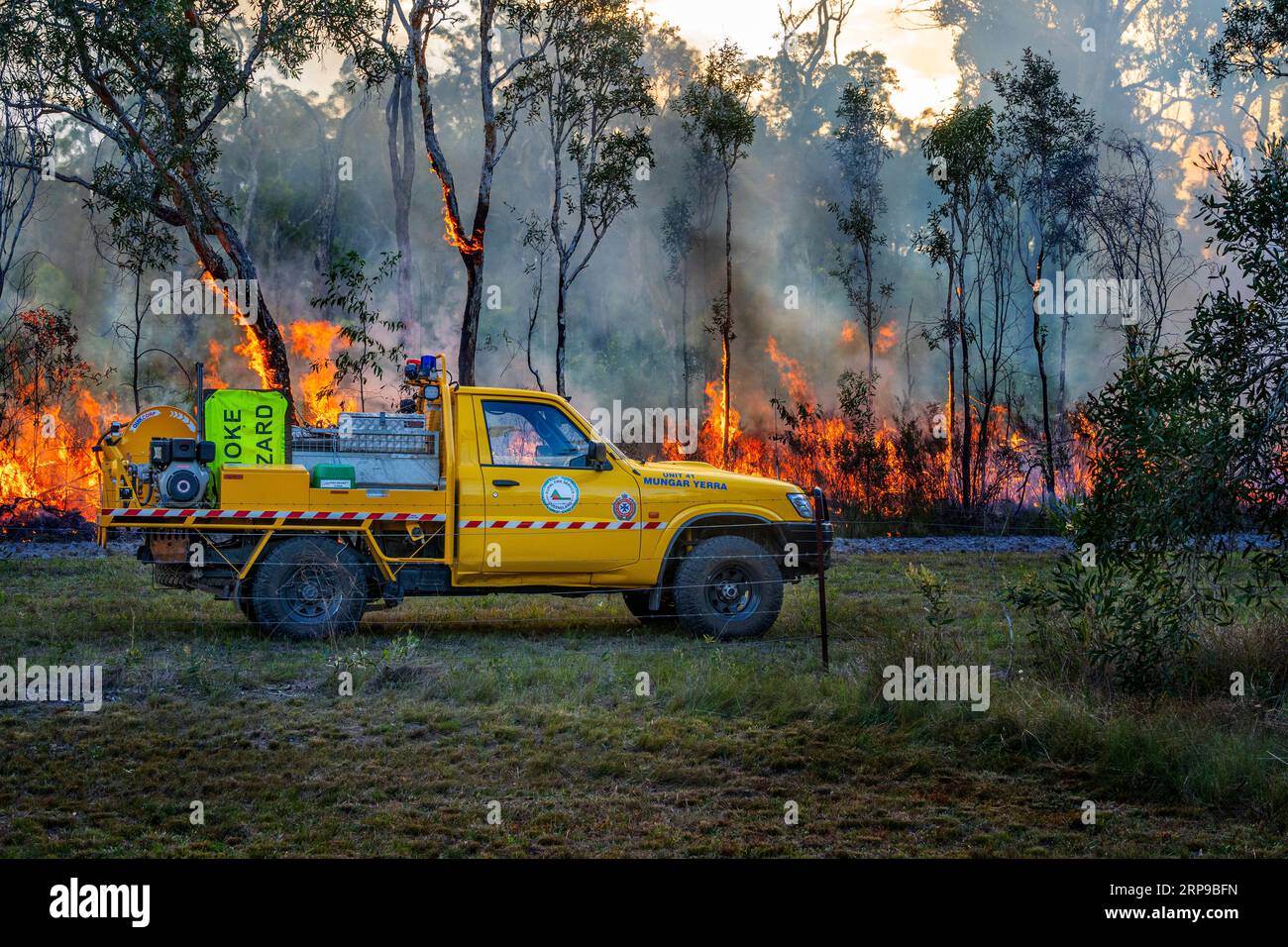 Yellow Rural Fire Service appliance with flames in background managing ...