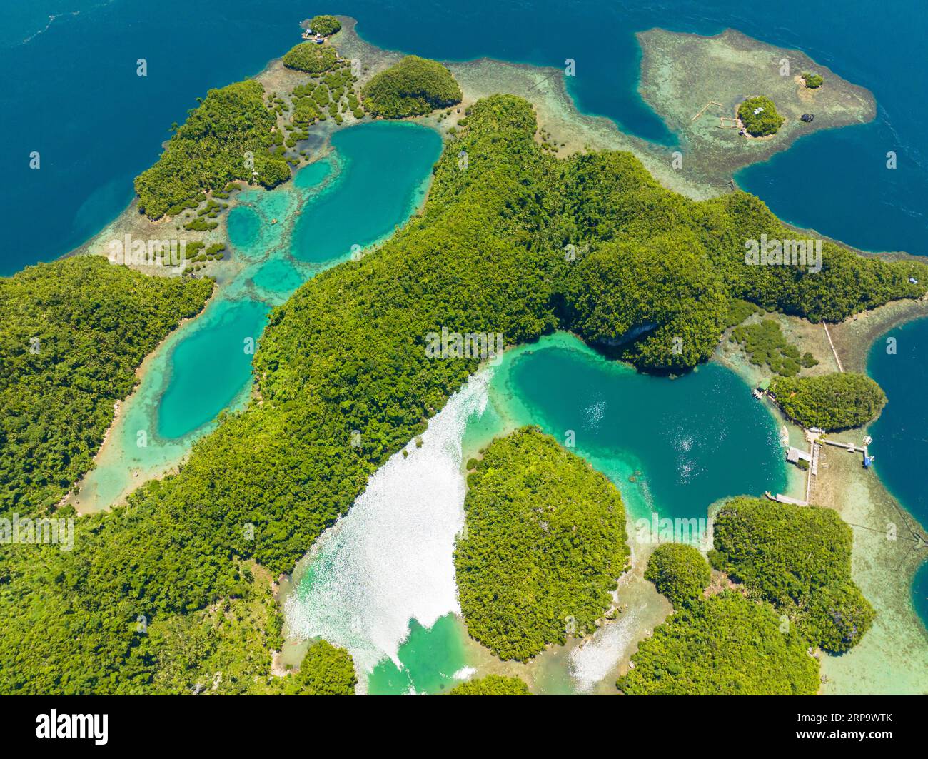Air survey of rainforest and turquoise water with sunlight reflection ...