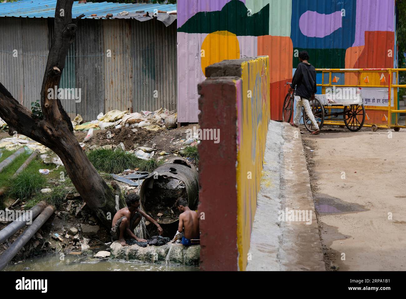 Laborers wash their clothes in sewage water under a bridge, newly ...
