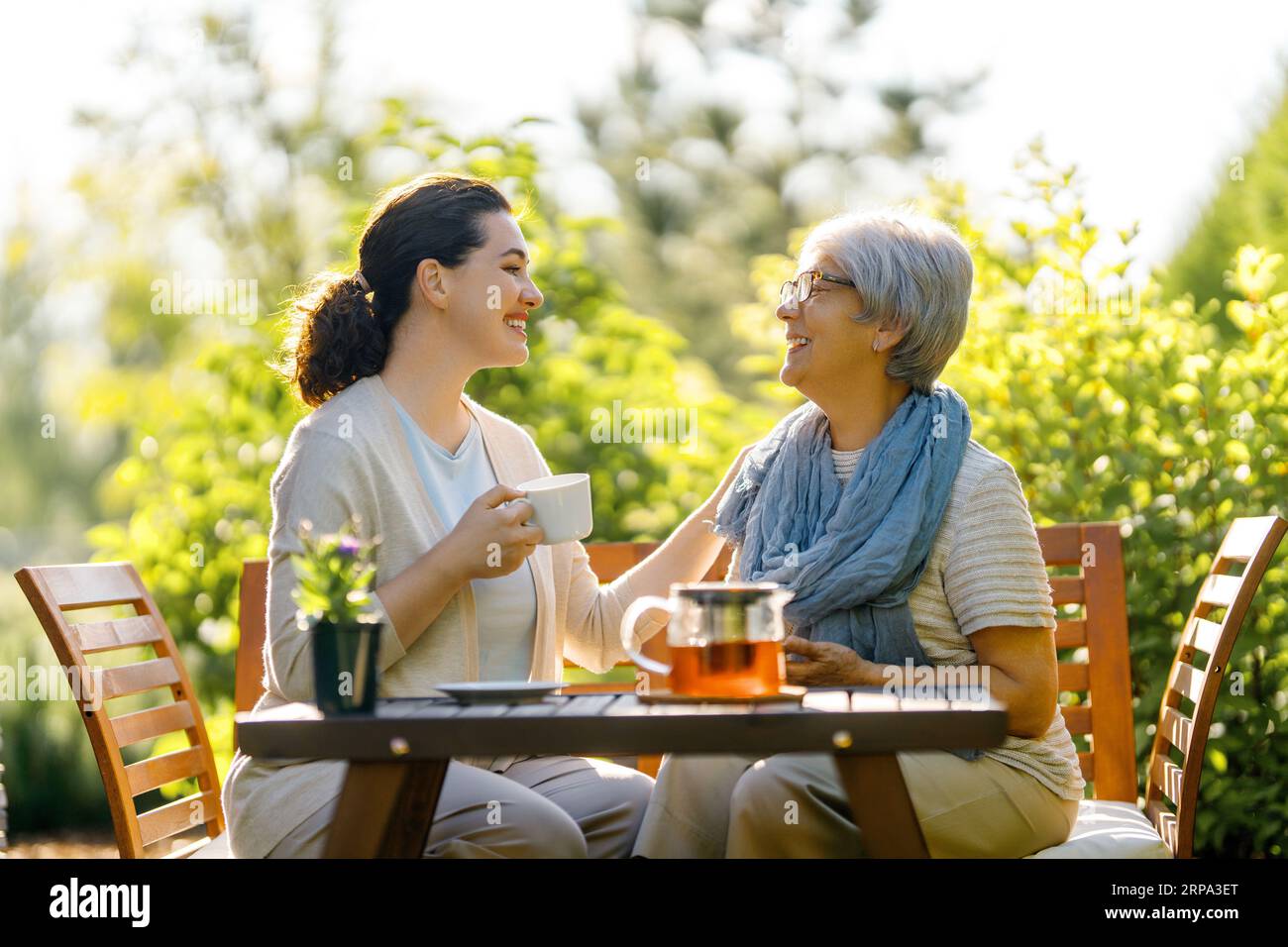 Happy young woman and her mother drinking tea in summer morning. Family ...