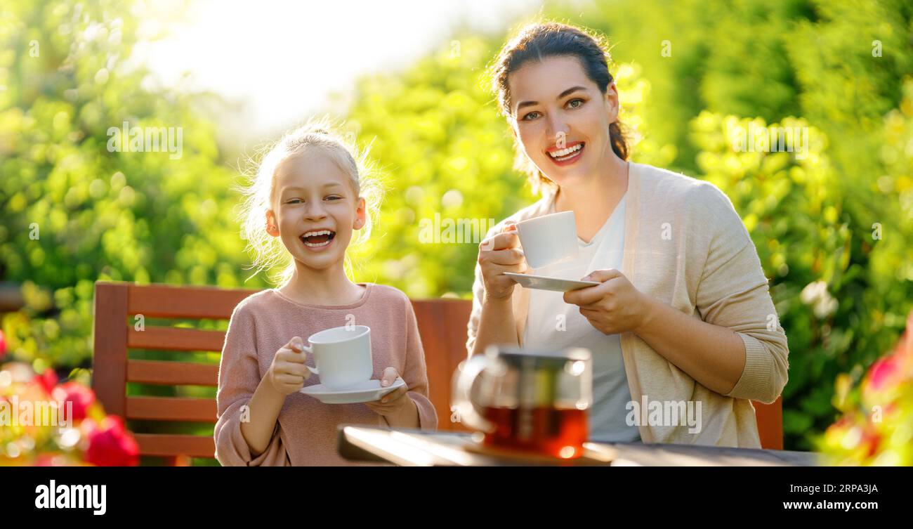 Happy little girl and her mother drinking tea in summer morning. Family ...