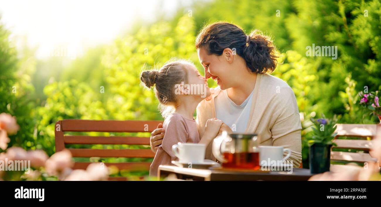 Happy little girl and her mother drinking tea in summer morning. Family ...