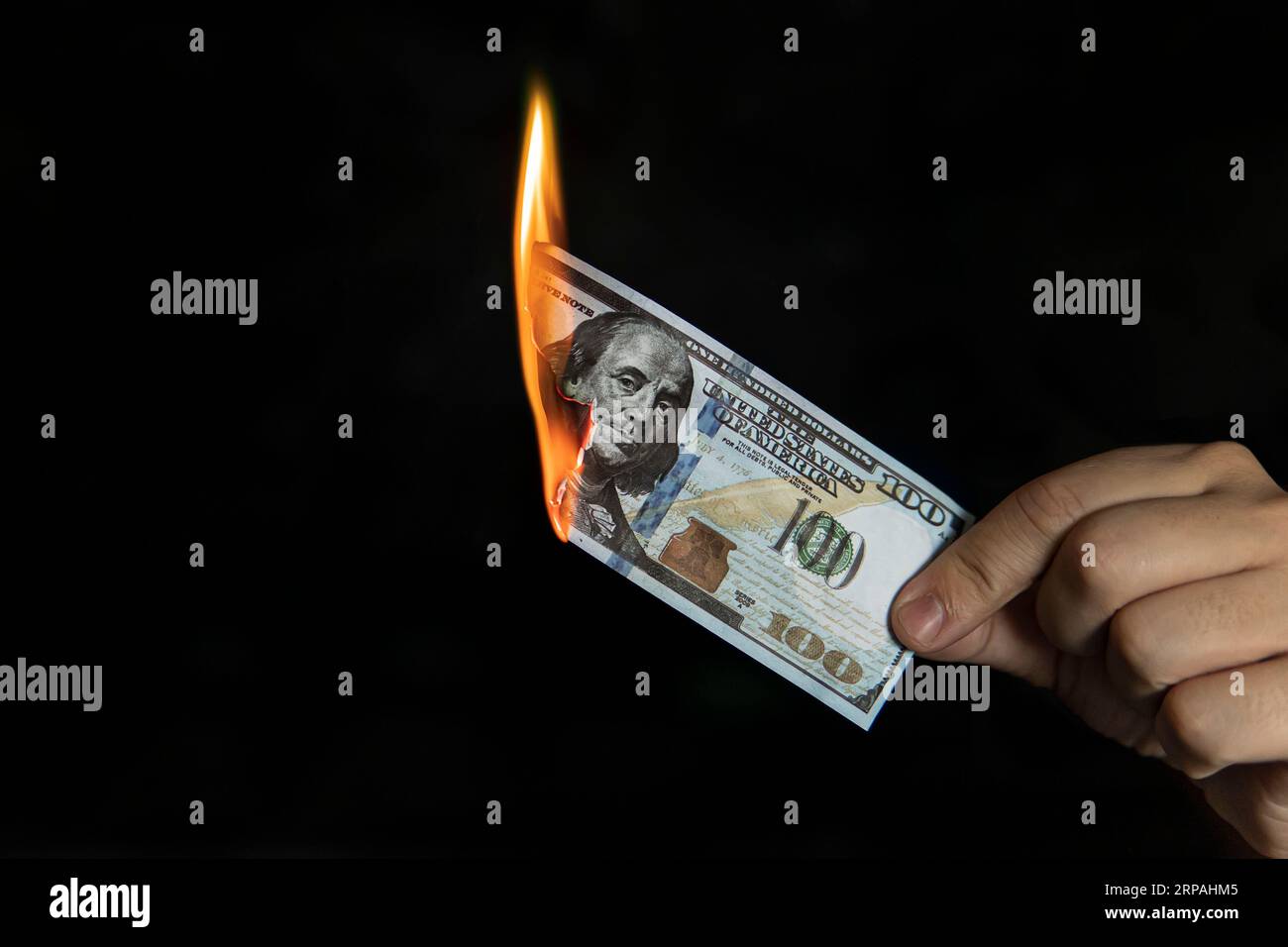 Human hand holding a burning 100 dollar bill. concept of inflation, a ...