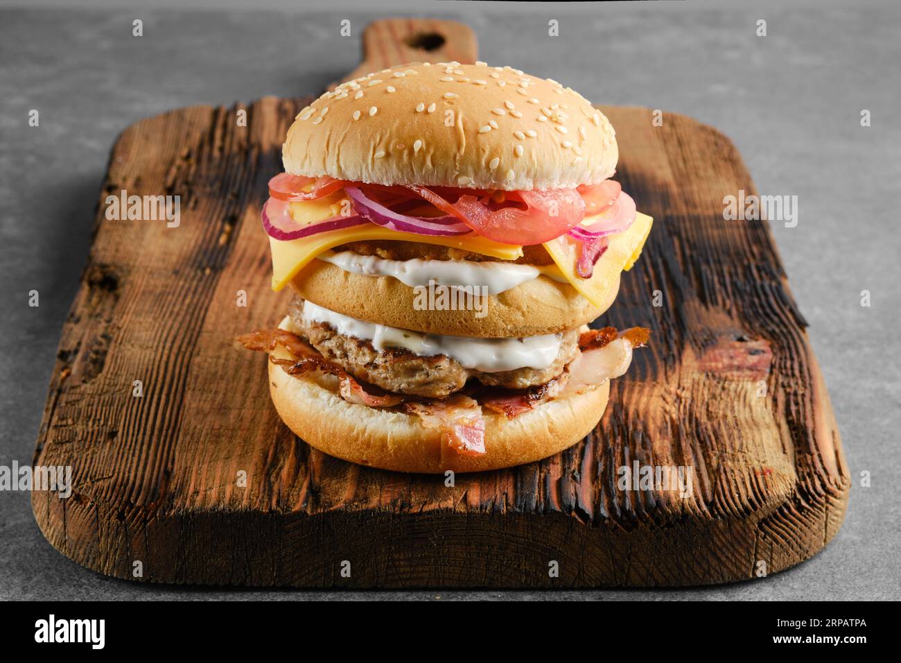 Monster double burger on wooden serving board Stock Photo - Alamy