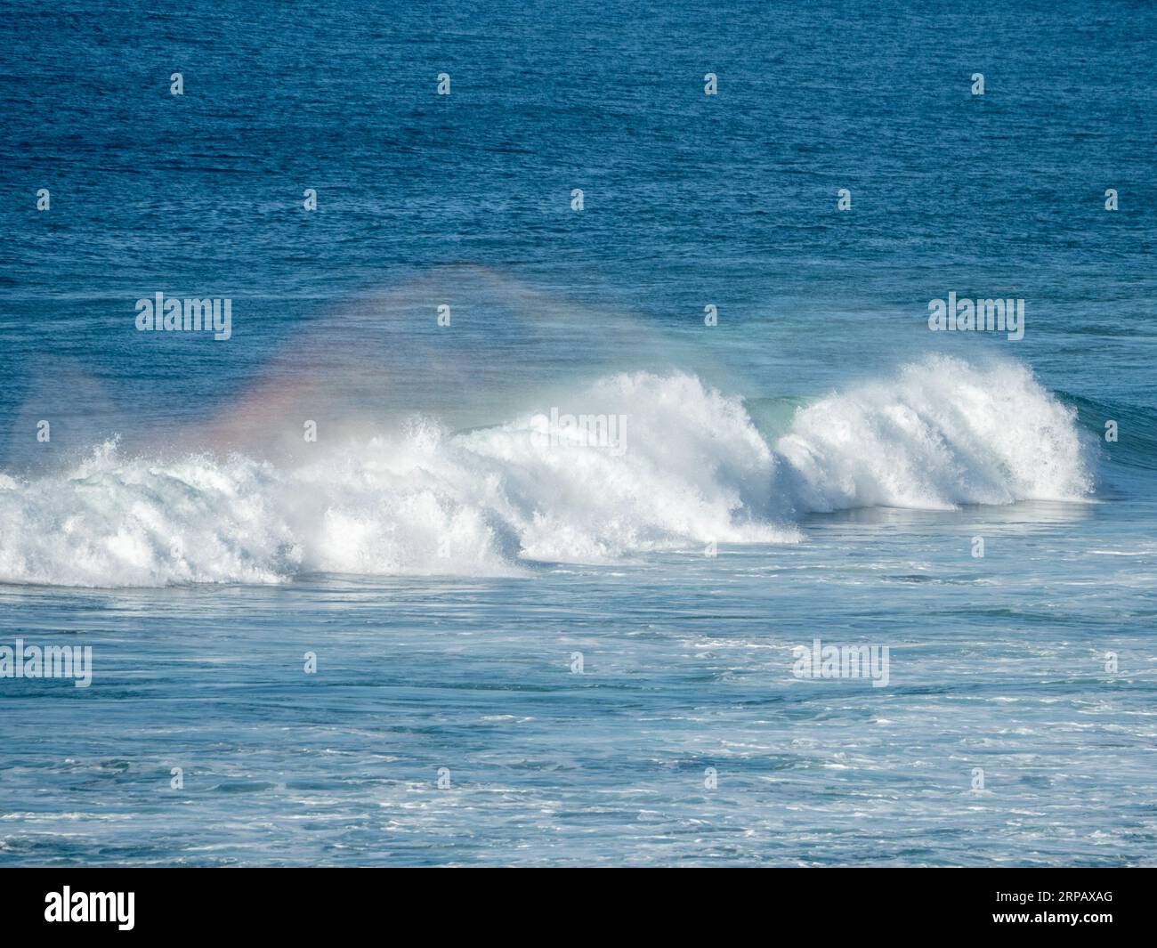 Sunlight shining on the water droplets spraying off the waves acting as ...