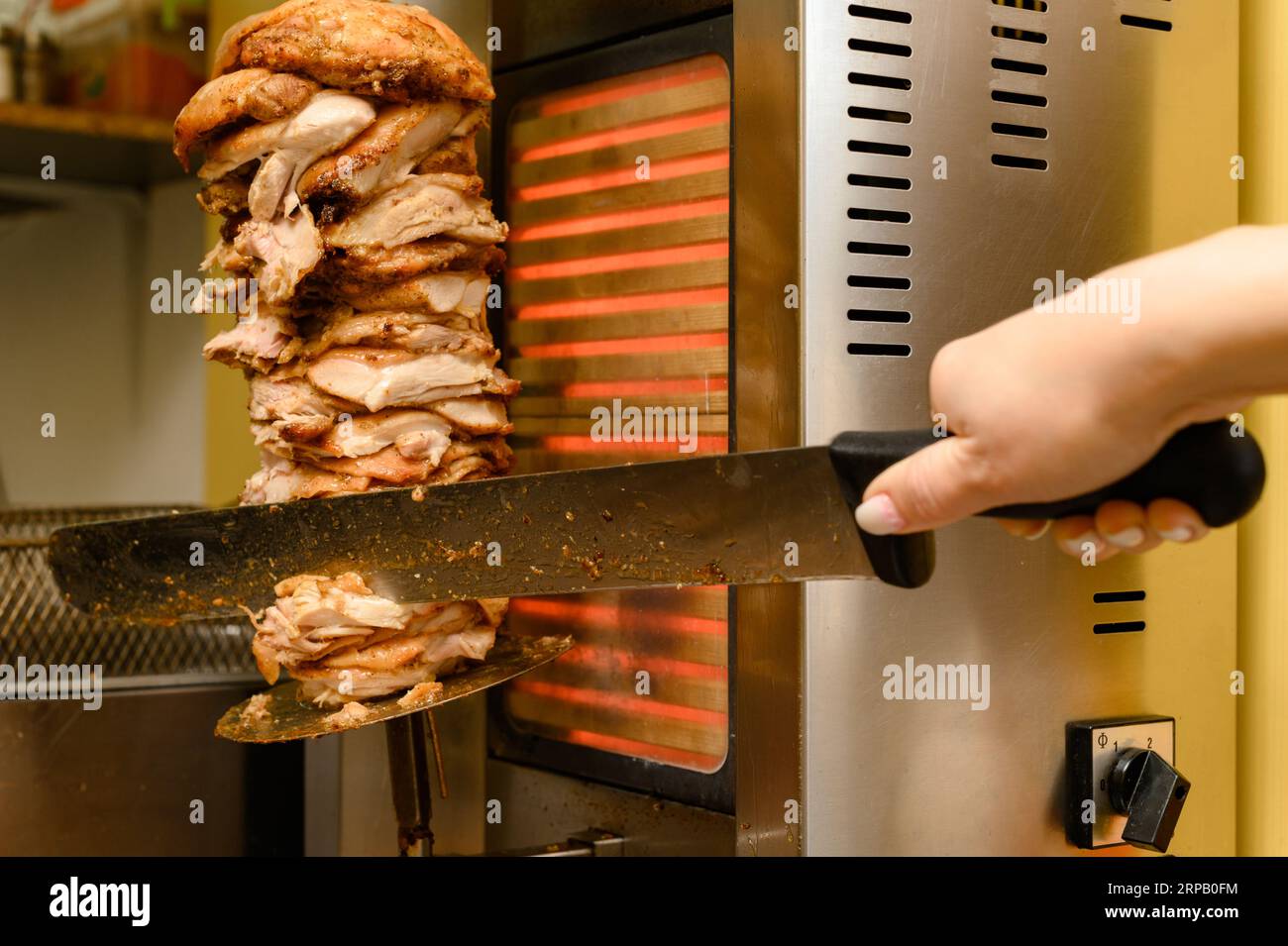 Chicken meat on a vertical grill is prepared for shawarma close-up ...