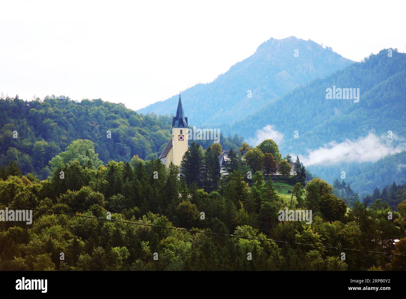 A church popping out of the forest, with a tall, sharp and rocky ...