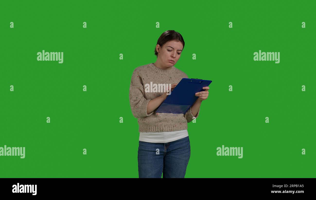 Front view of female model looking at clipboard documents, working on ...