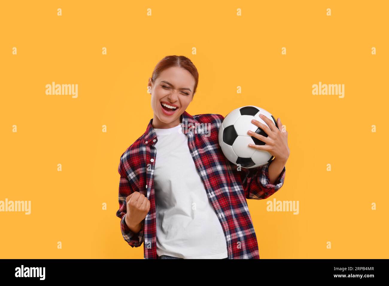 Emotional fan holding football ball and celebrating on yellow ...