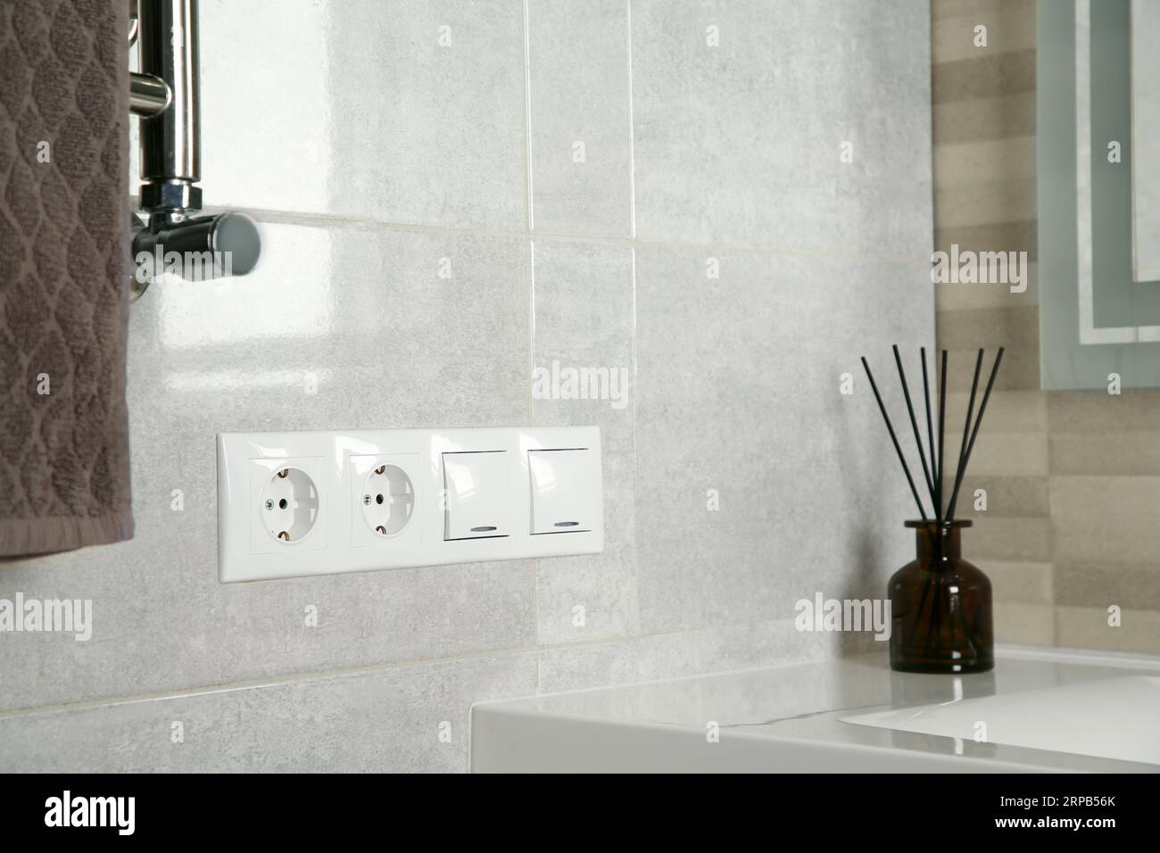 Light switches and power sockets on light grey wall in bathroom. Space ...