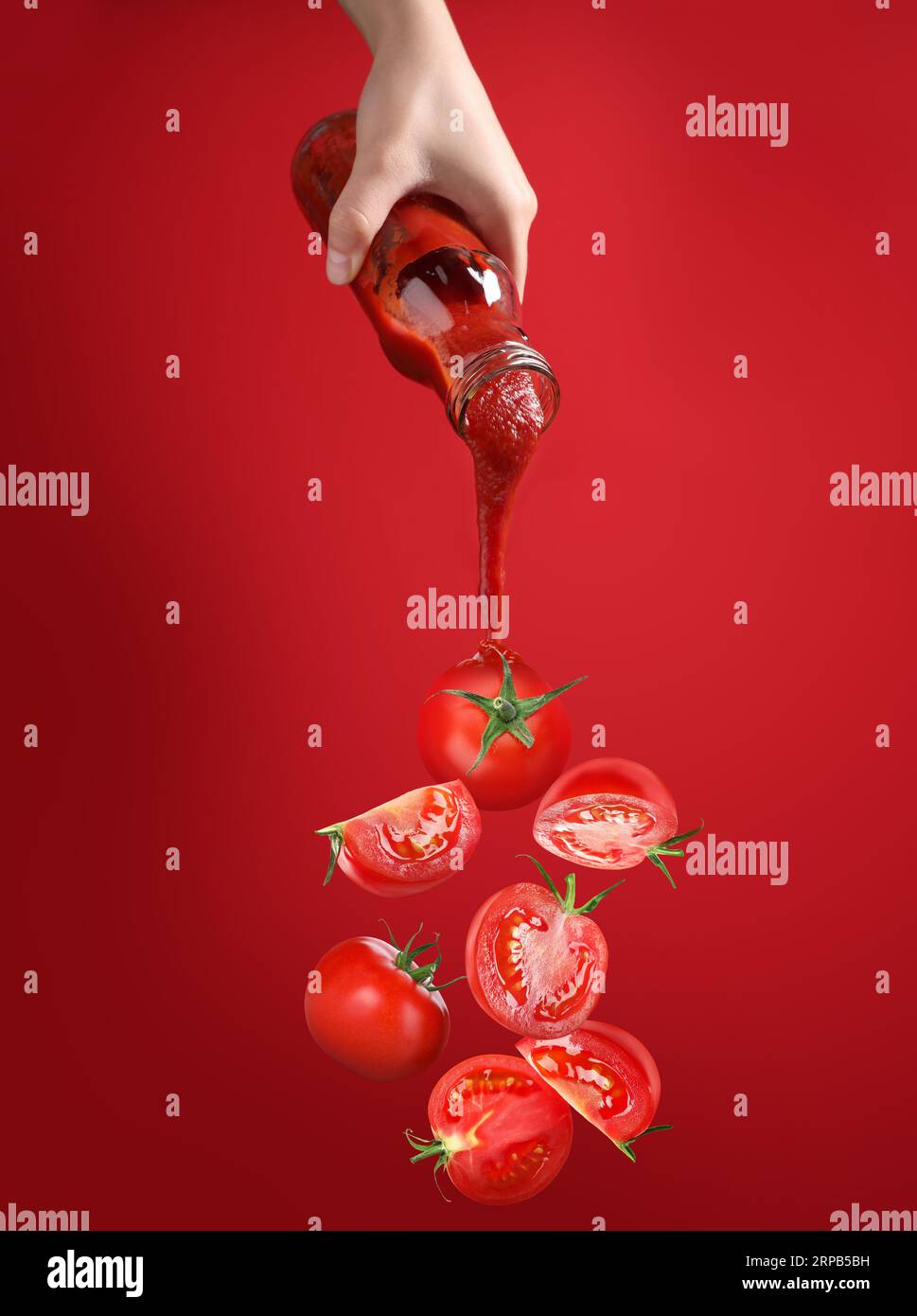 Woman pouring organic ketchup onto tomato against red background ...