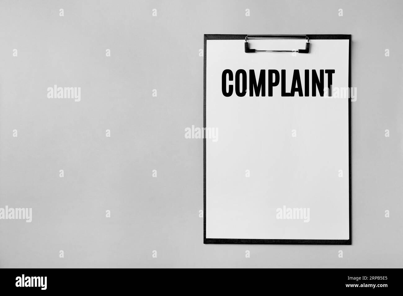 Paper with word Complaints attached to clipboard on grey background ...