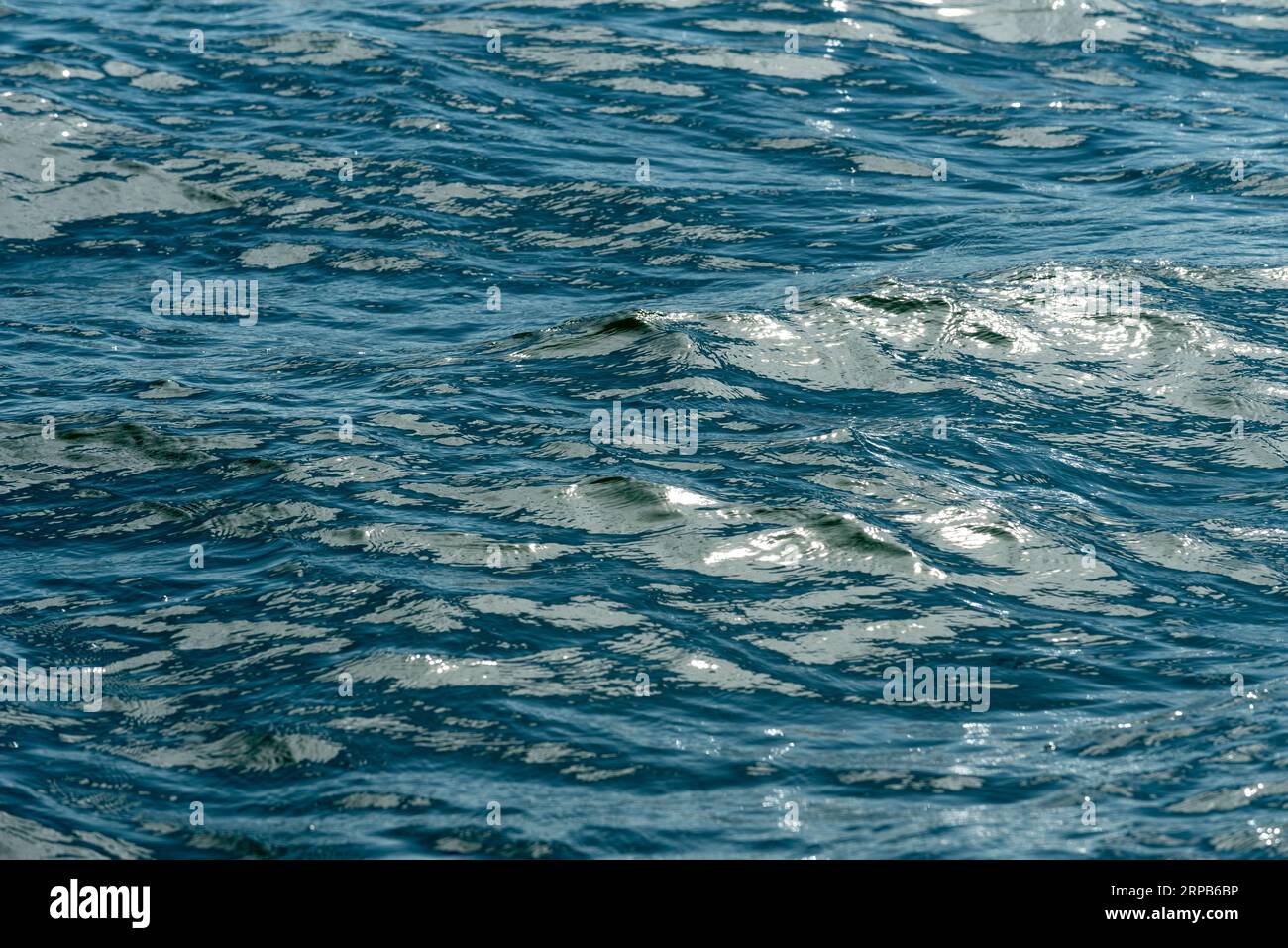 Bright blue ocean with calm waves and sunlight hitting the surface ...