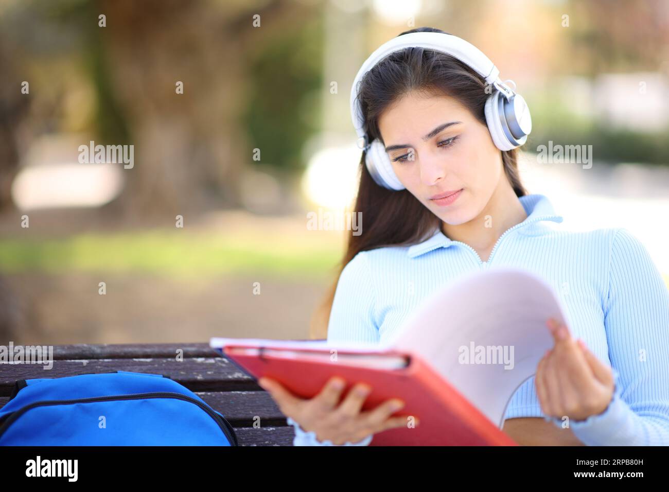 Student with headphone reading notes from notebook in a park Stock ...