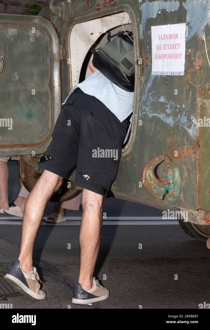 KYIV, UKRAINE - Aug. 24, 2023: A young lad examines a burnt-out Russian ...