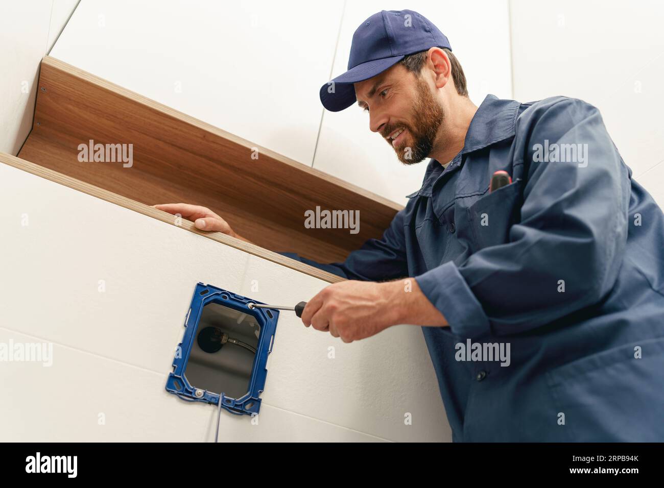 Repairman holding screwdriver tool while installing toilet flush panel ...