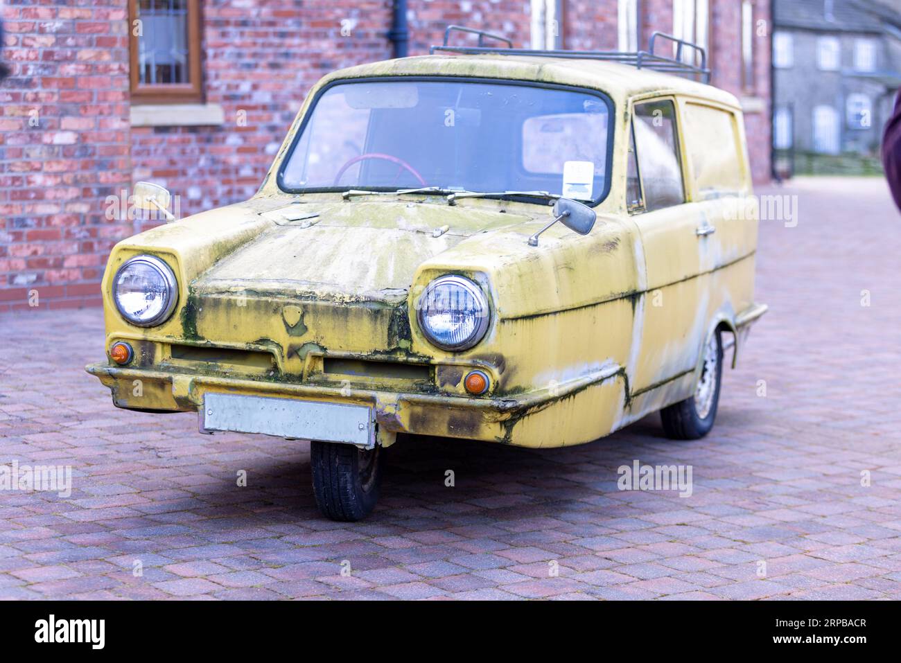 A classic historic Reliant Robin 3 wheel van the colour yellow used for ...