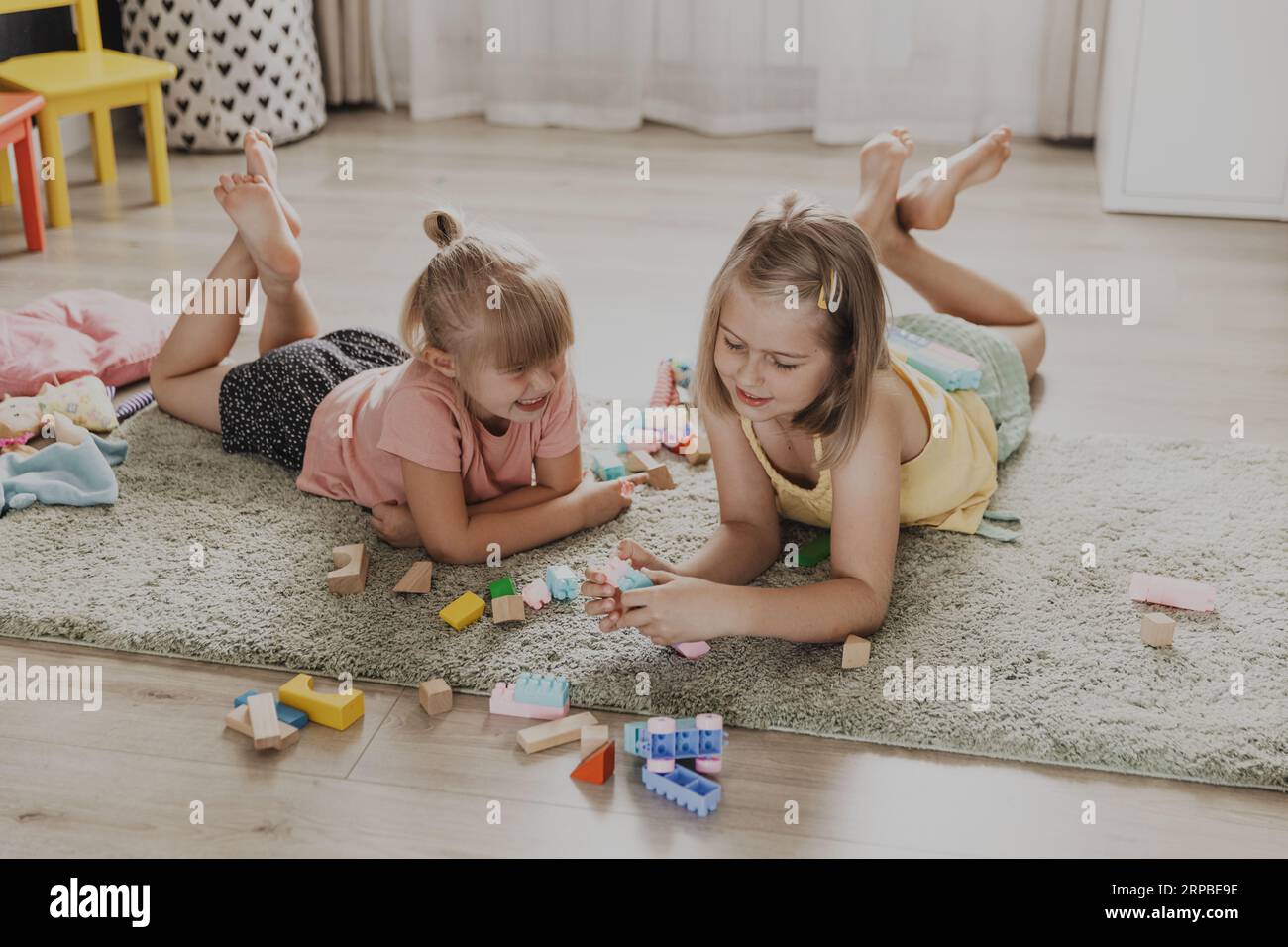 Children playing with colorful toys. Kids lying on carpet at home ...