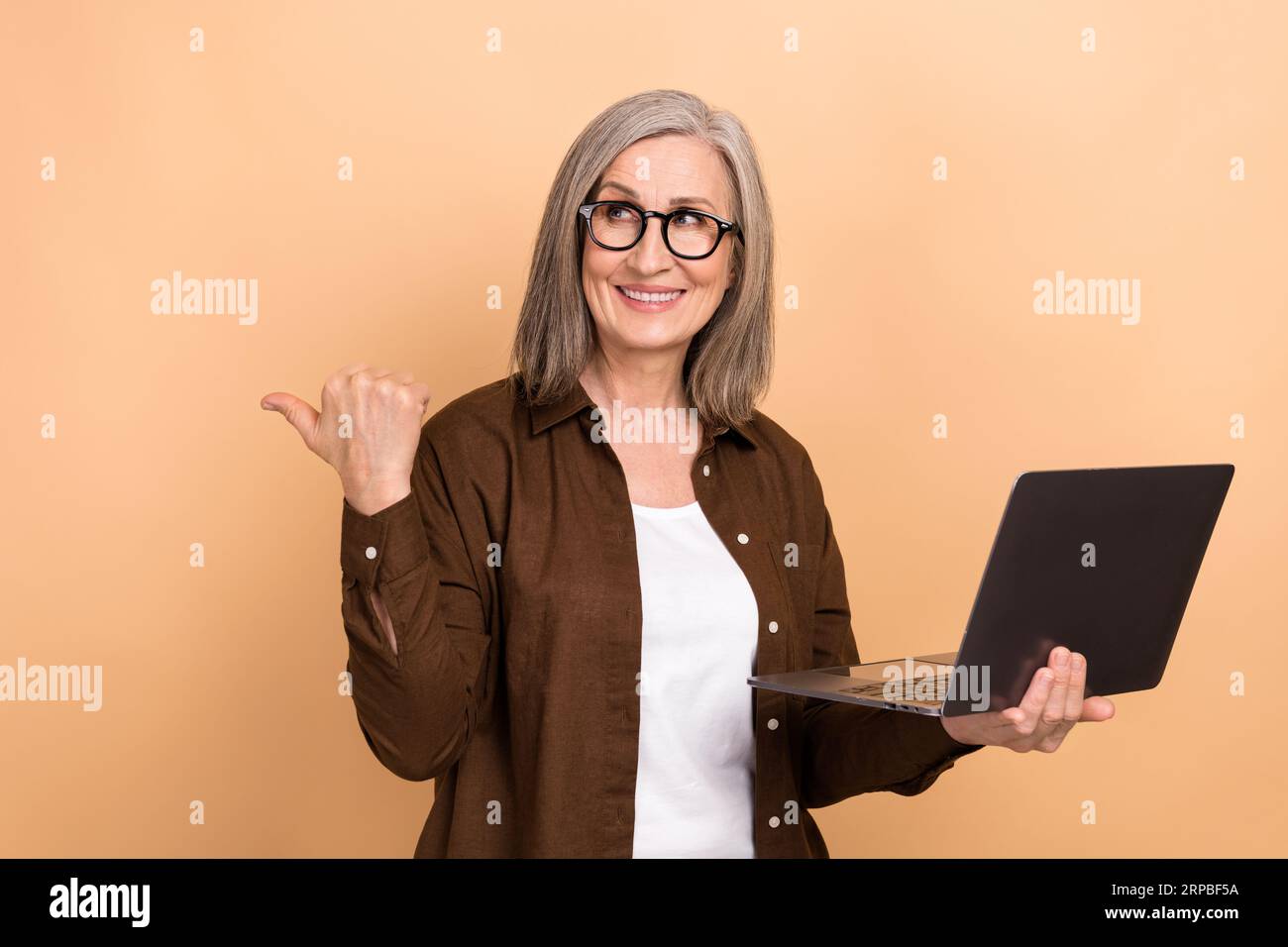 Photo of cheerful pretty aged lady hold wireless netbook look indicate ...