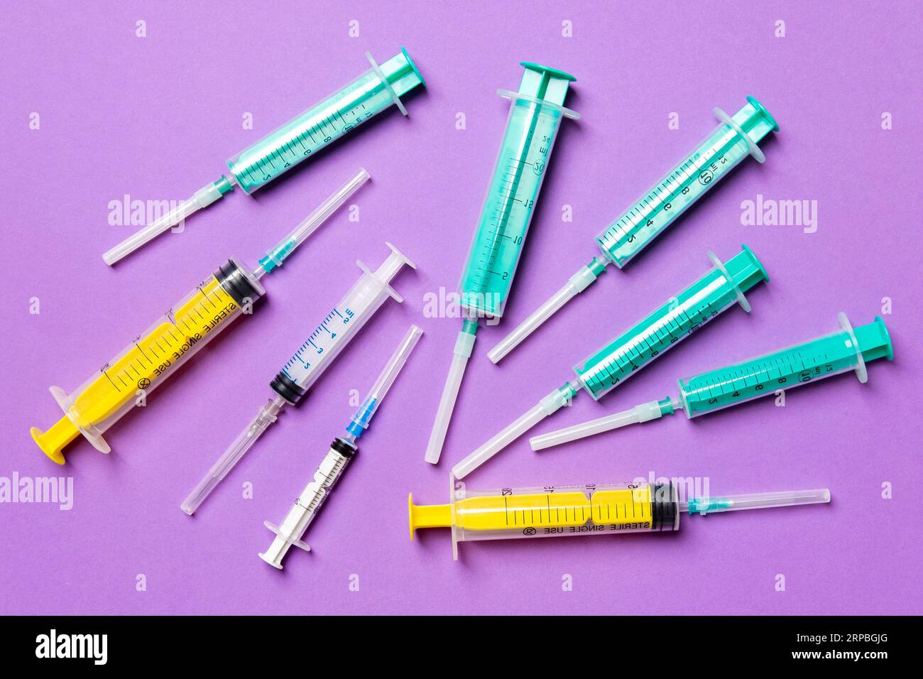 Top view of medical syringes with needles at purple background with ...