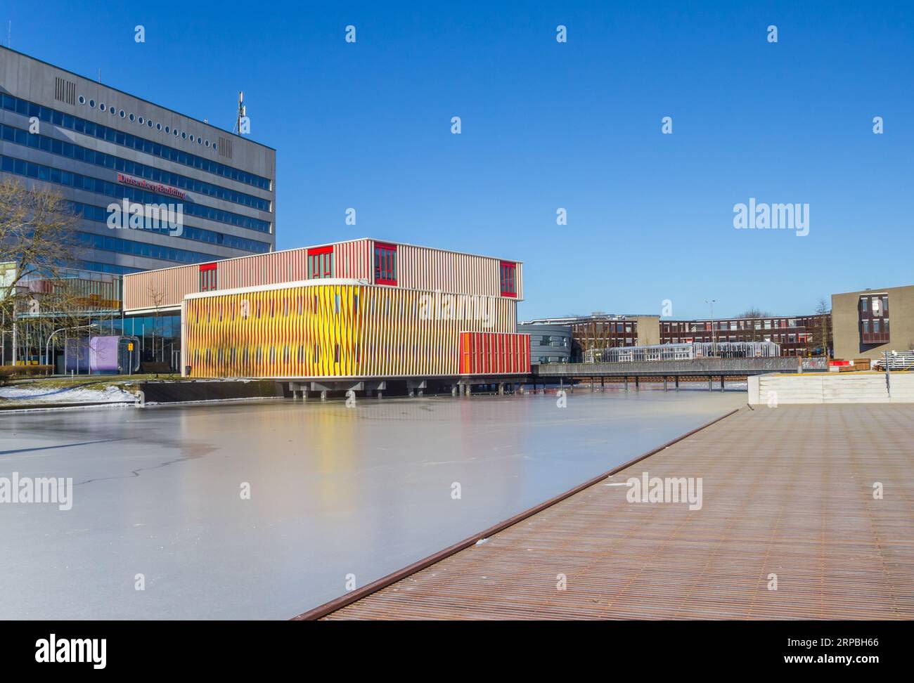 Wooden jetty in front of the red and yellow Duisenberg building in ...