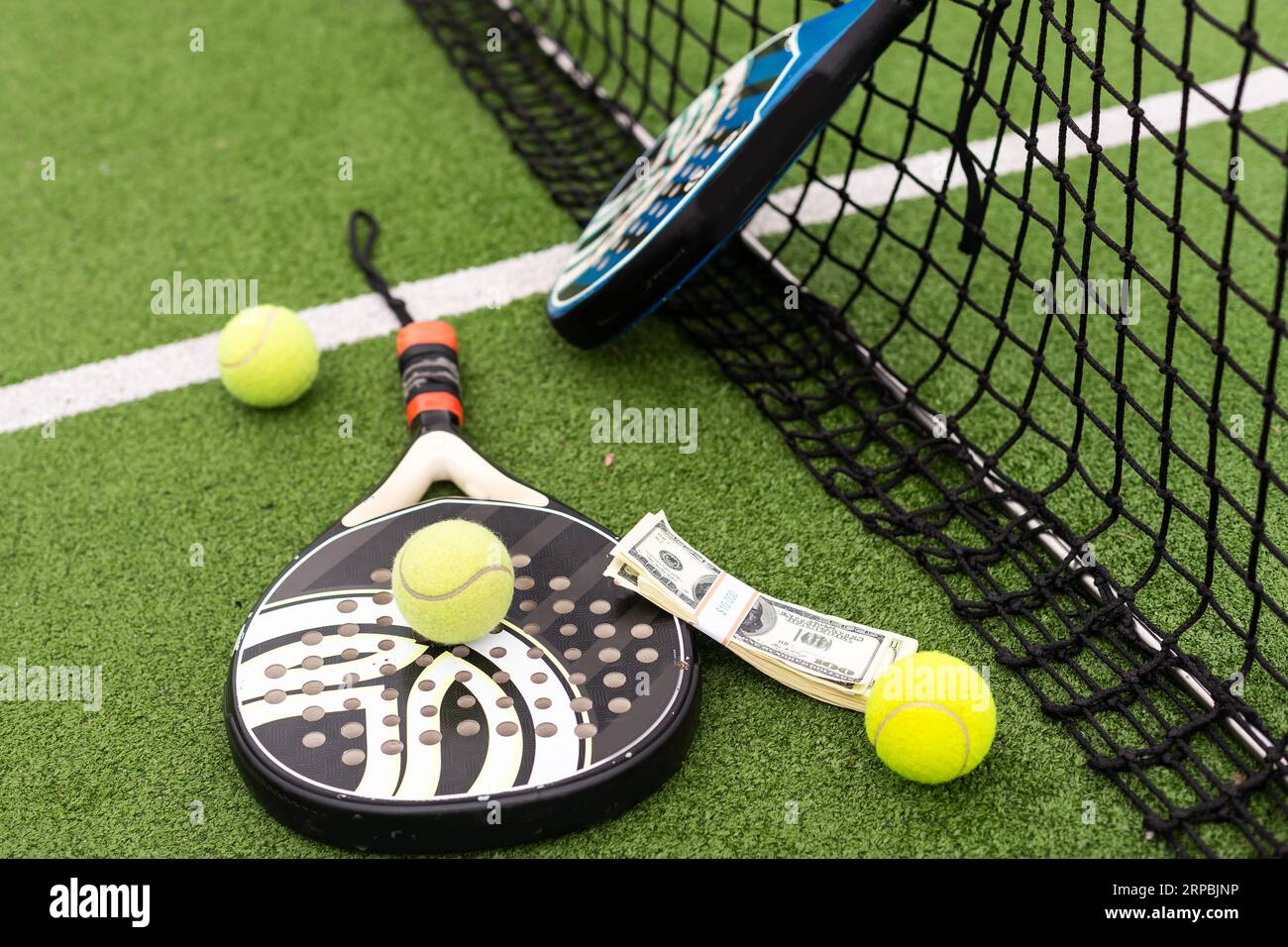 Yellow balls on grass turf near padel tennis racket behind net in green ...