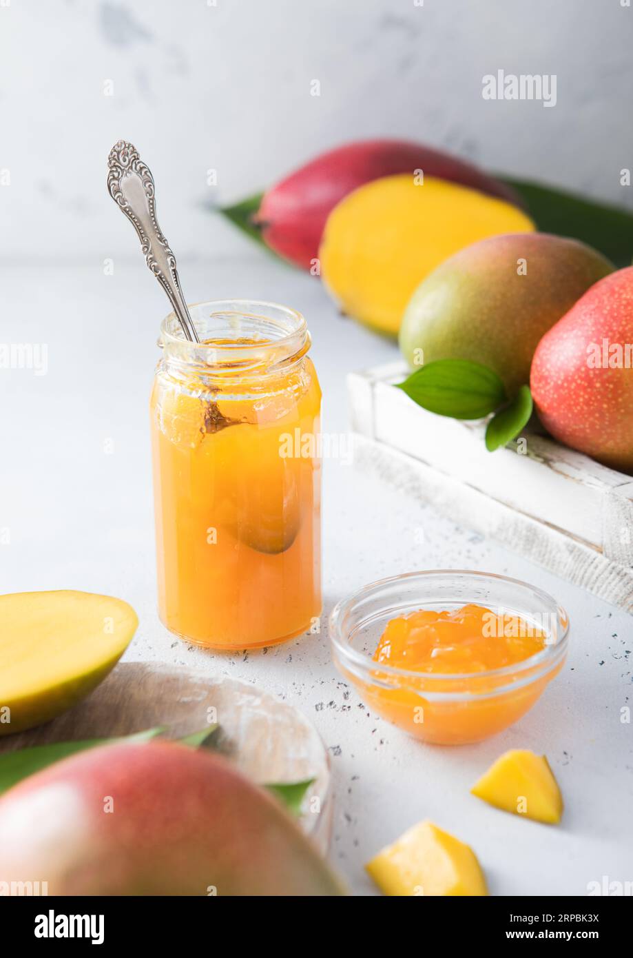 Mango marmalade jam puree with spoon on light background with raw ...