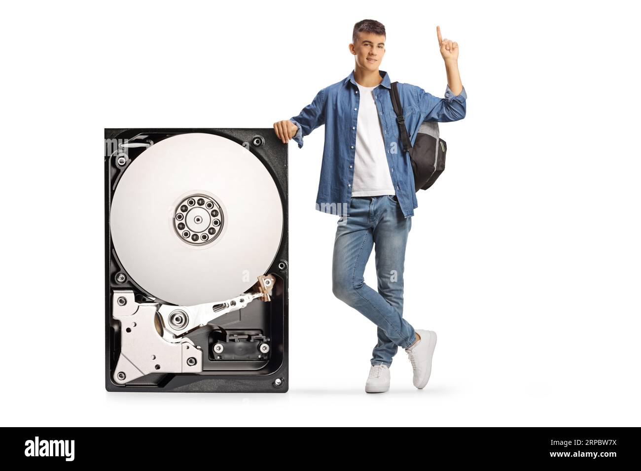 Male student leaning on a hard disk and pointing up isolated on white ...