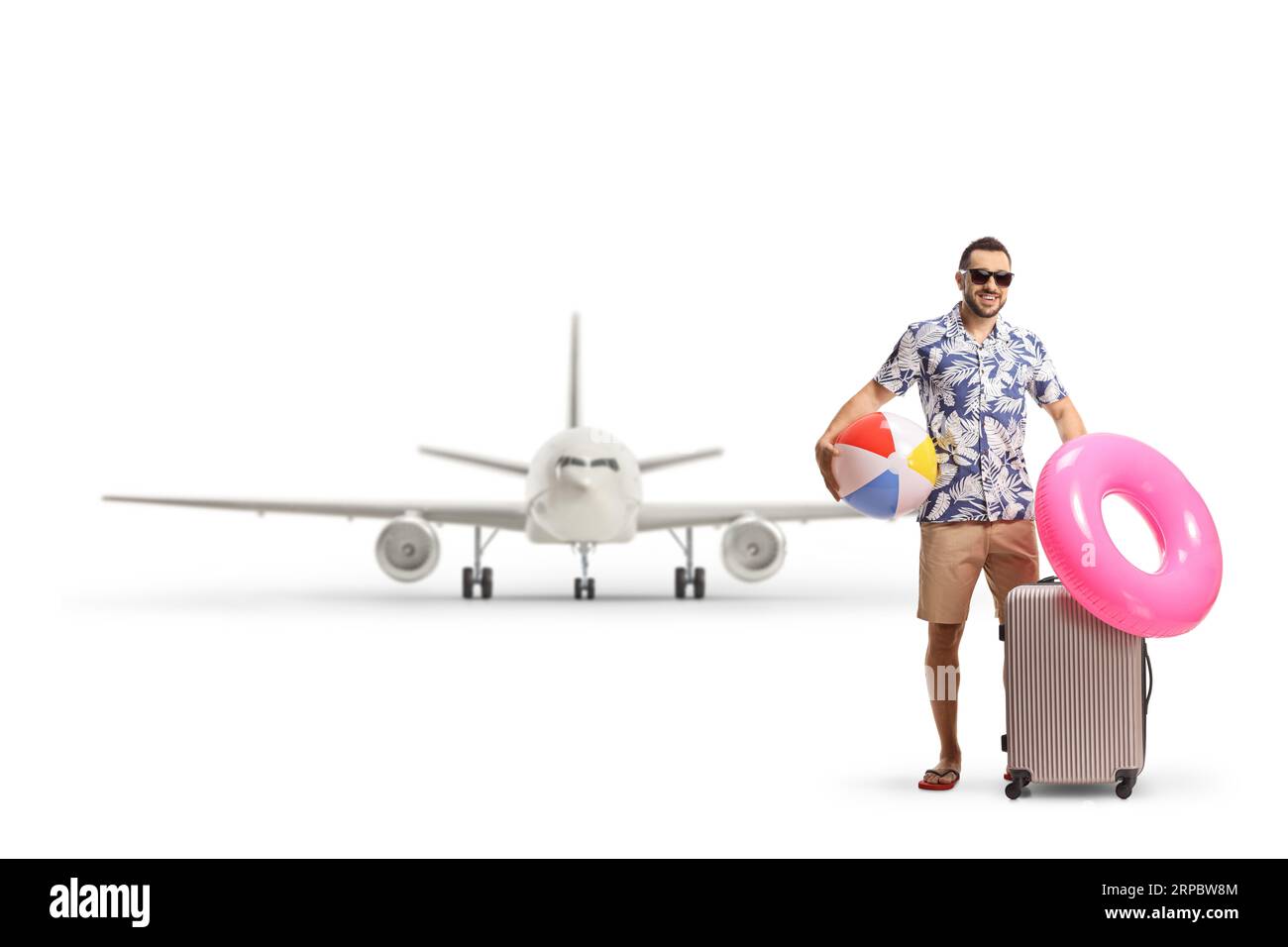 Man traveling on a holiday and posing with a suitcase, beach ball and ...
