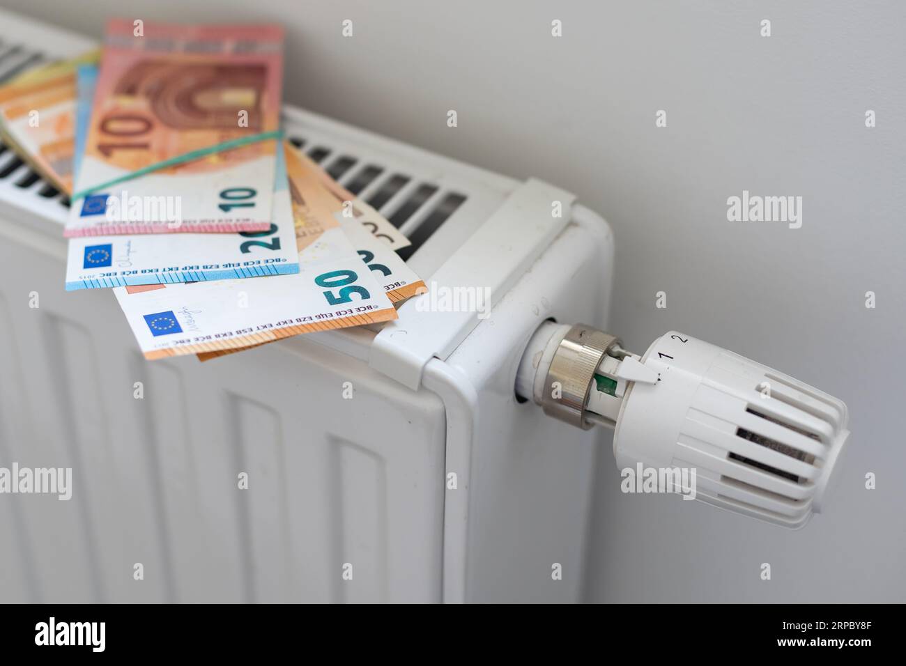 Euro money banknotes on heating radiator battery with thermostat ...