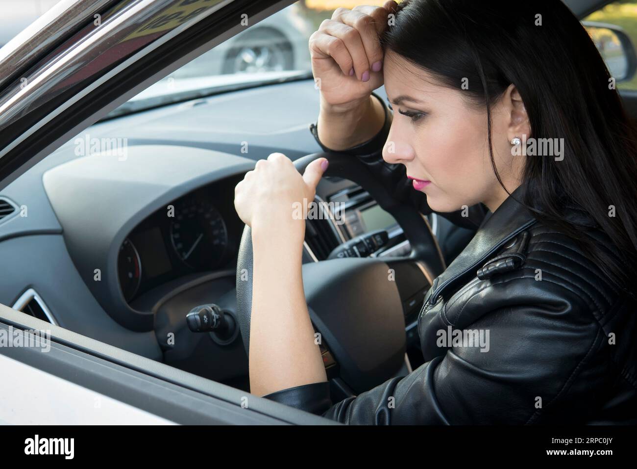 Side view of beautiful young woman looking in car side-view mirror ...