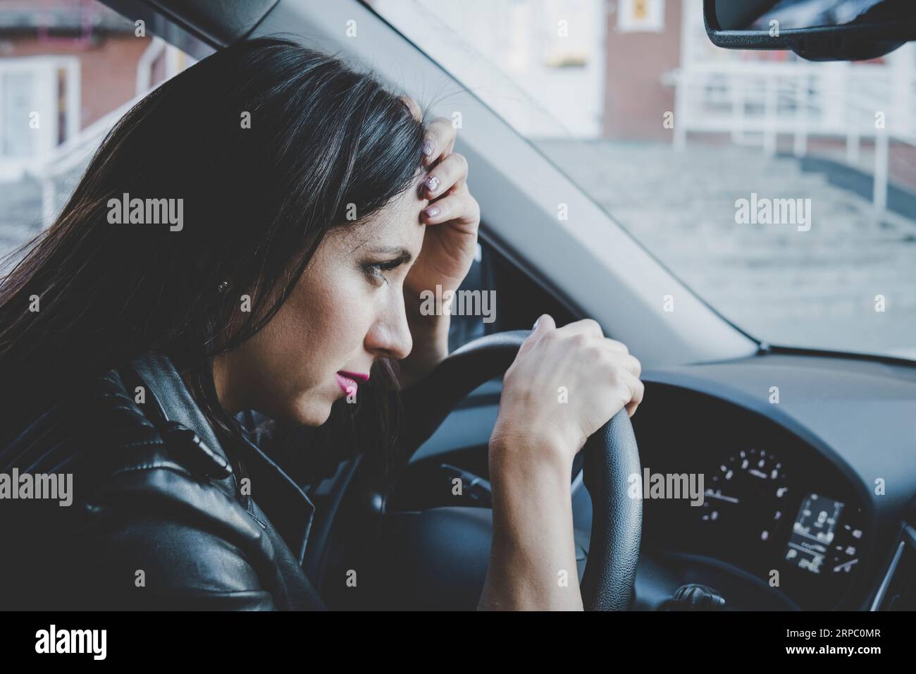 Close up of brunette girl looking frustrated sitting in car and leaning ...