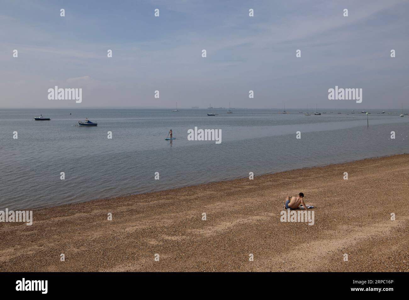 People sitting looking out onto the Thames Estuary, along the promenade ...