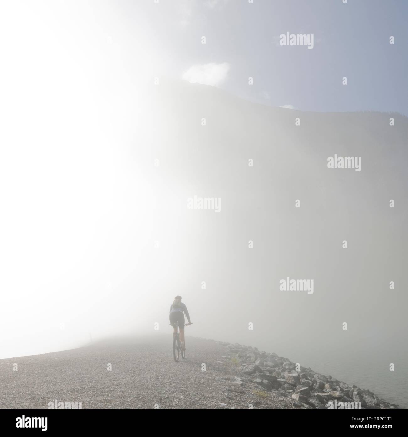 Mountain biker rides out of mountain fog Stock Photo - Alamy