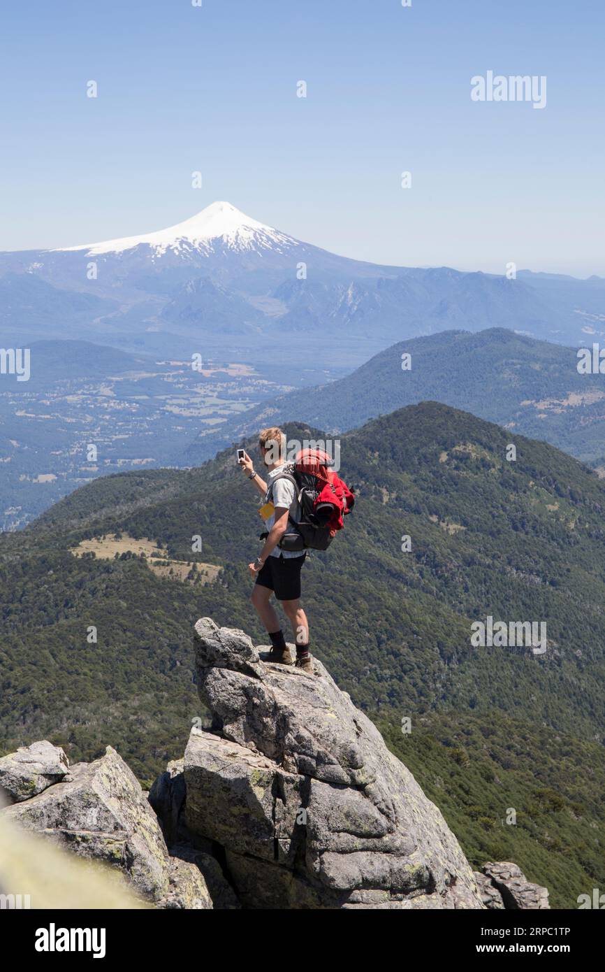 Hiker takes photo on summit in front of volcano Stock Photo - Alamy