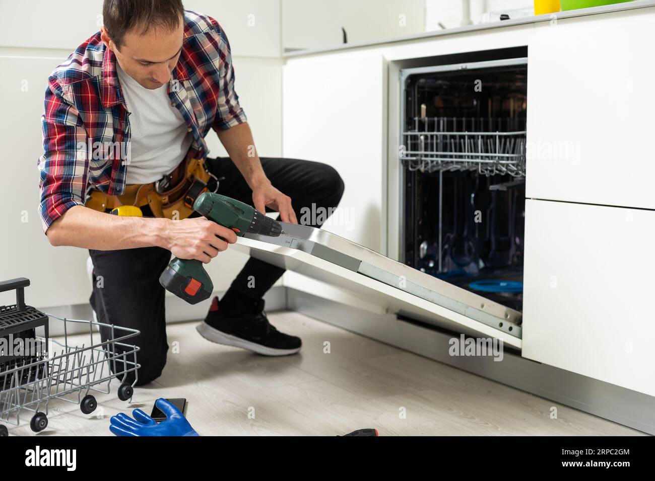 Worker repairing the dishwasher in the kitchen Stock Photo - Alamy