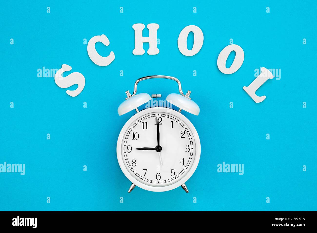 Alarm clock and the word school on a blue background, top view Stock ...