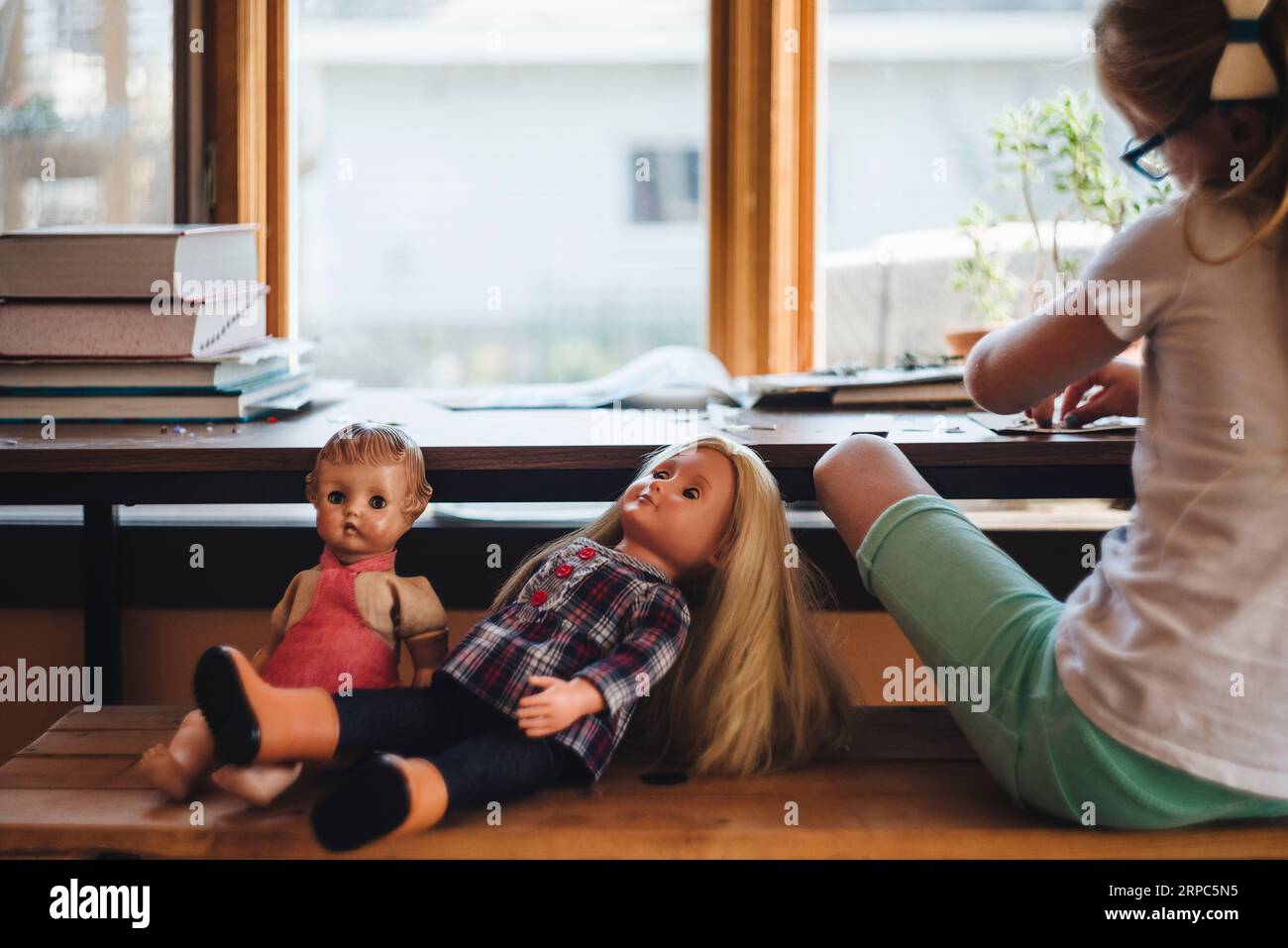 Little girl sitting at table in house with dolls Stock Photo - Alamy