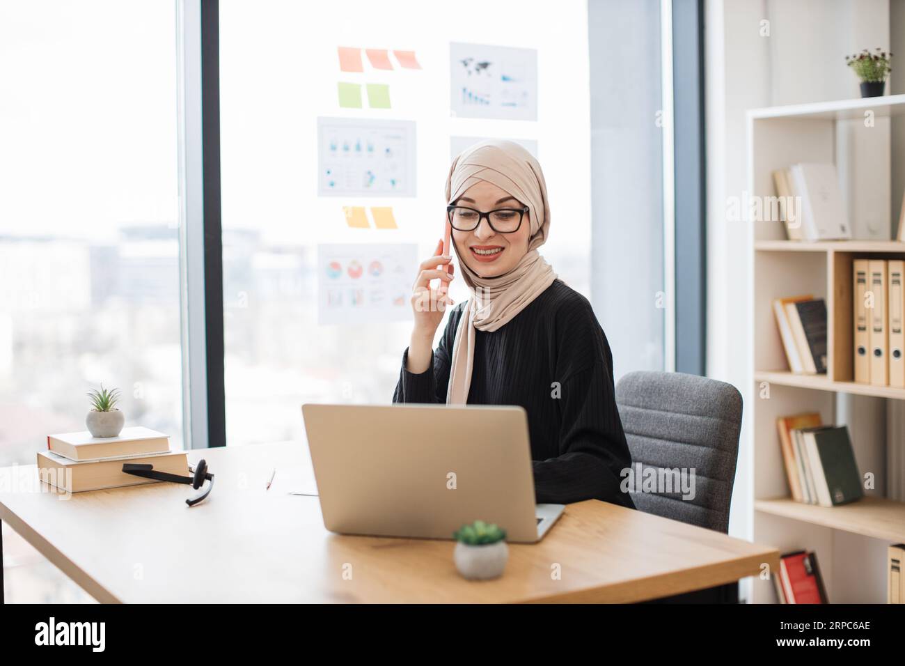Expert speaking on mobile while using laptop for office work Stock ...