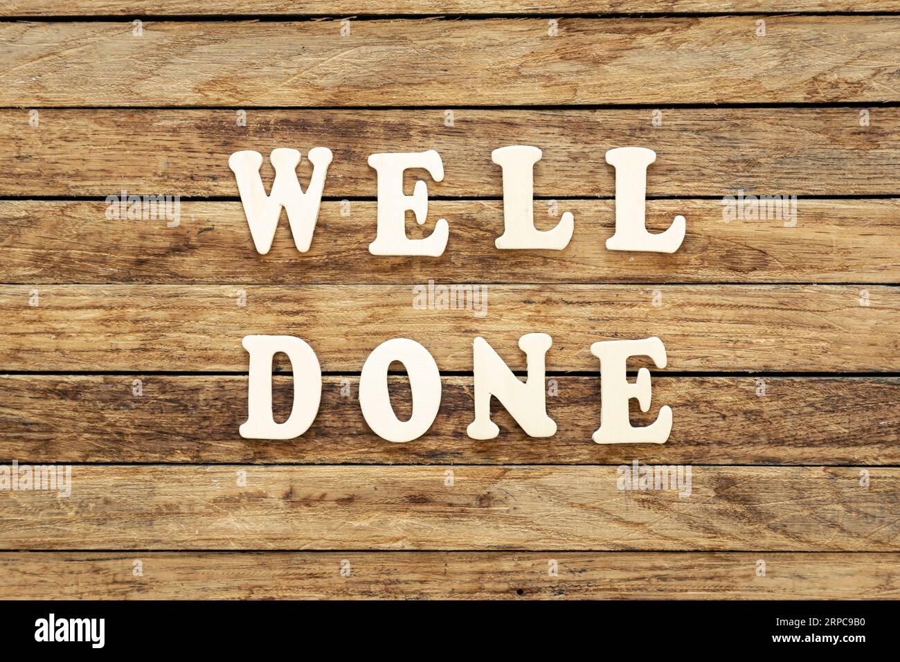 Well done, words composed of wooden letters on a wooden background ...