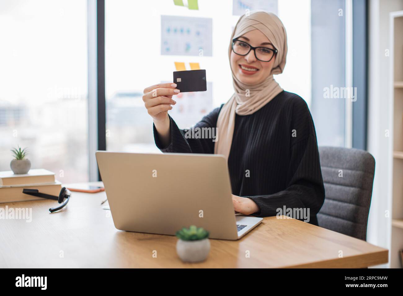 Arabian female with credit card running laptop in workplace Stock Photo ...