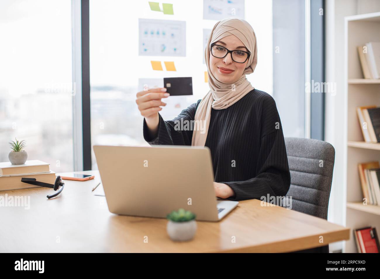 Arabian female with credit card running laptop in workplace Stock Photo ...