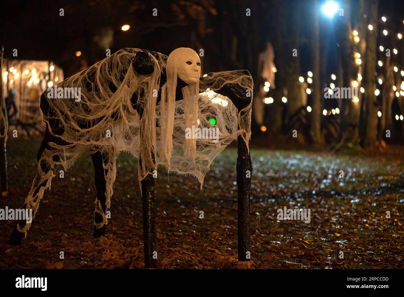 A spooky Halloween decoration stands in a wooded area creating a ...