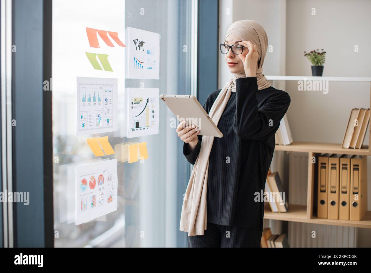 Confident bespectacled lady in headscarf scanning information on ...