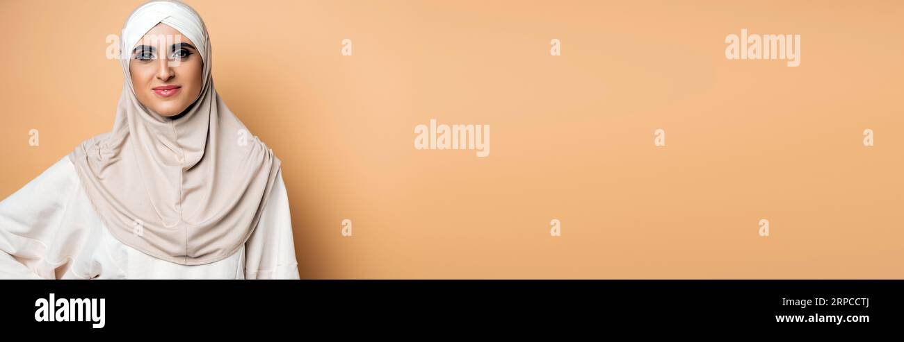 trendy muslim woman in white sweatshirt and hijab smiling at camera on ...