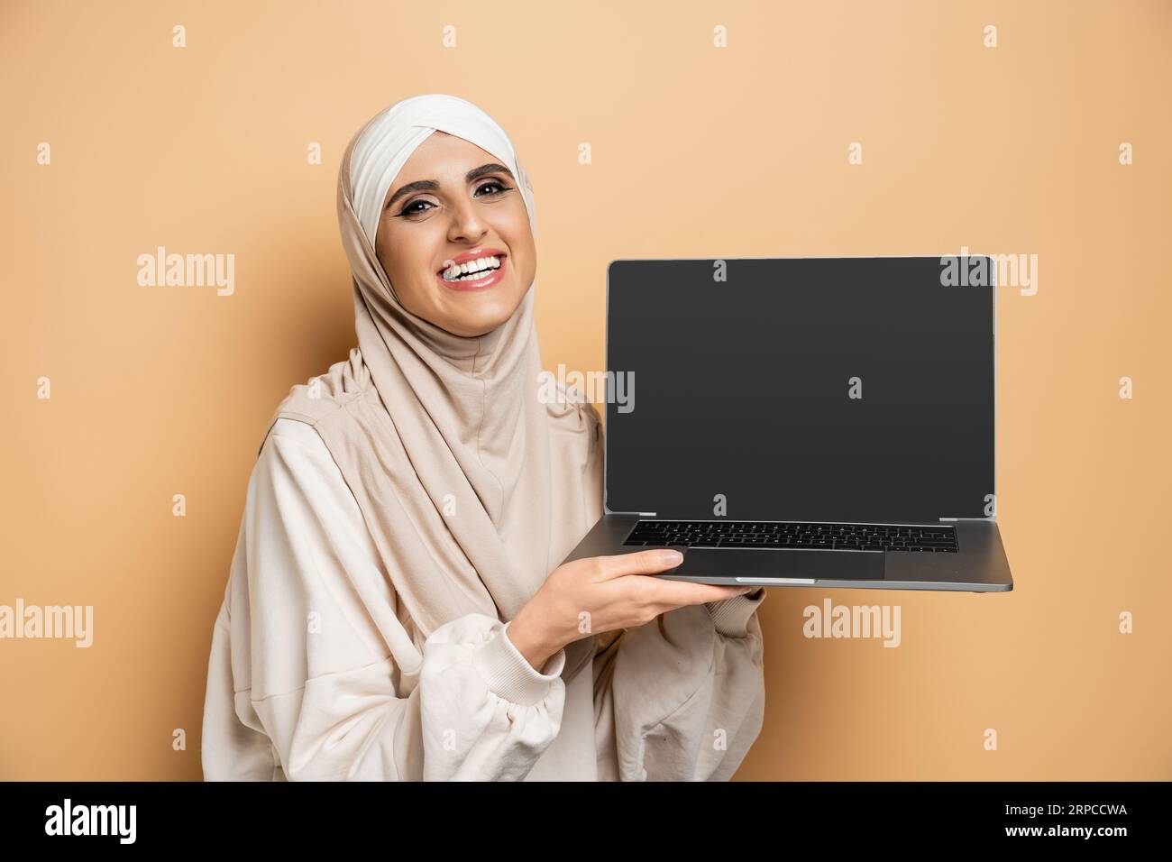 modern muslim woman in hijab holding laptop with blank screen and ...