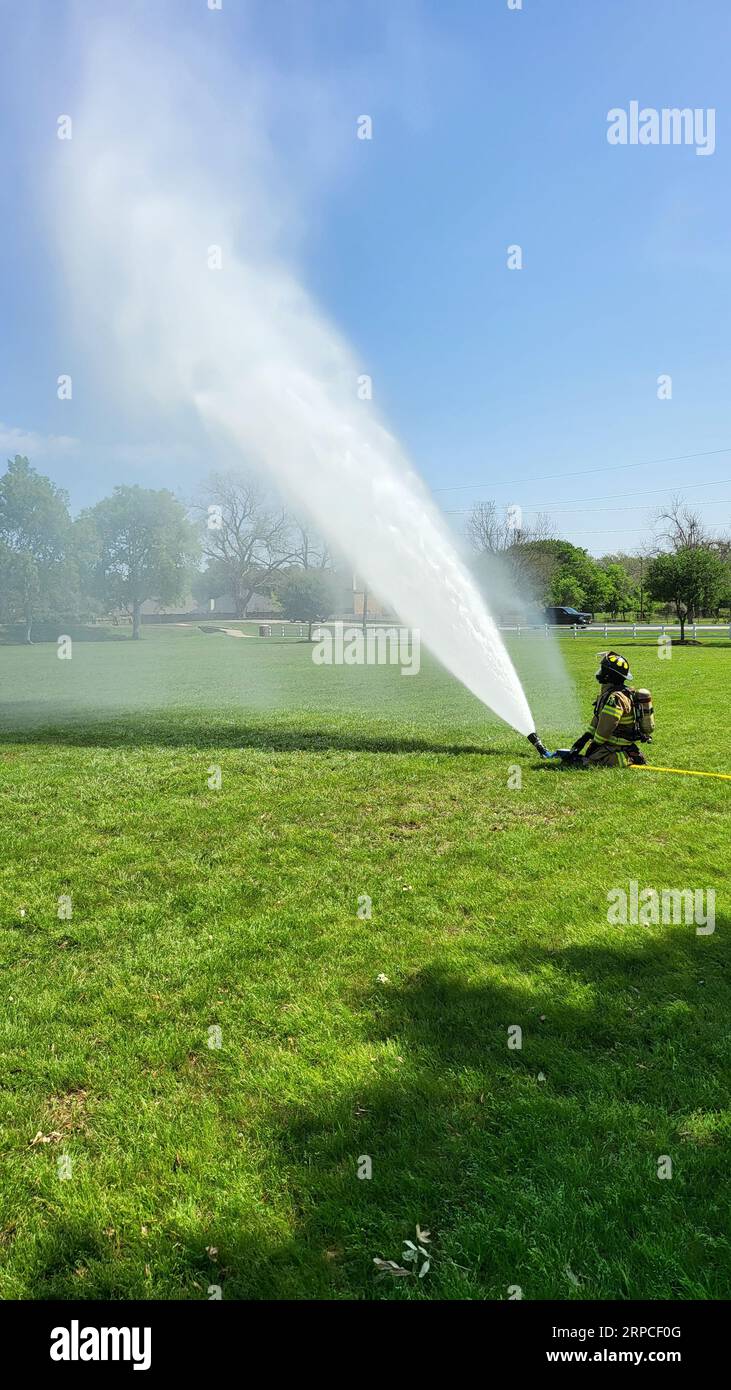 A firefighter in full protective gear spraying a powerful fire hose ...