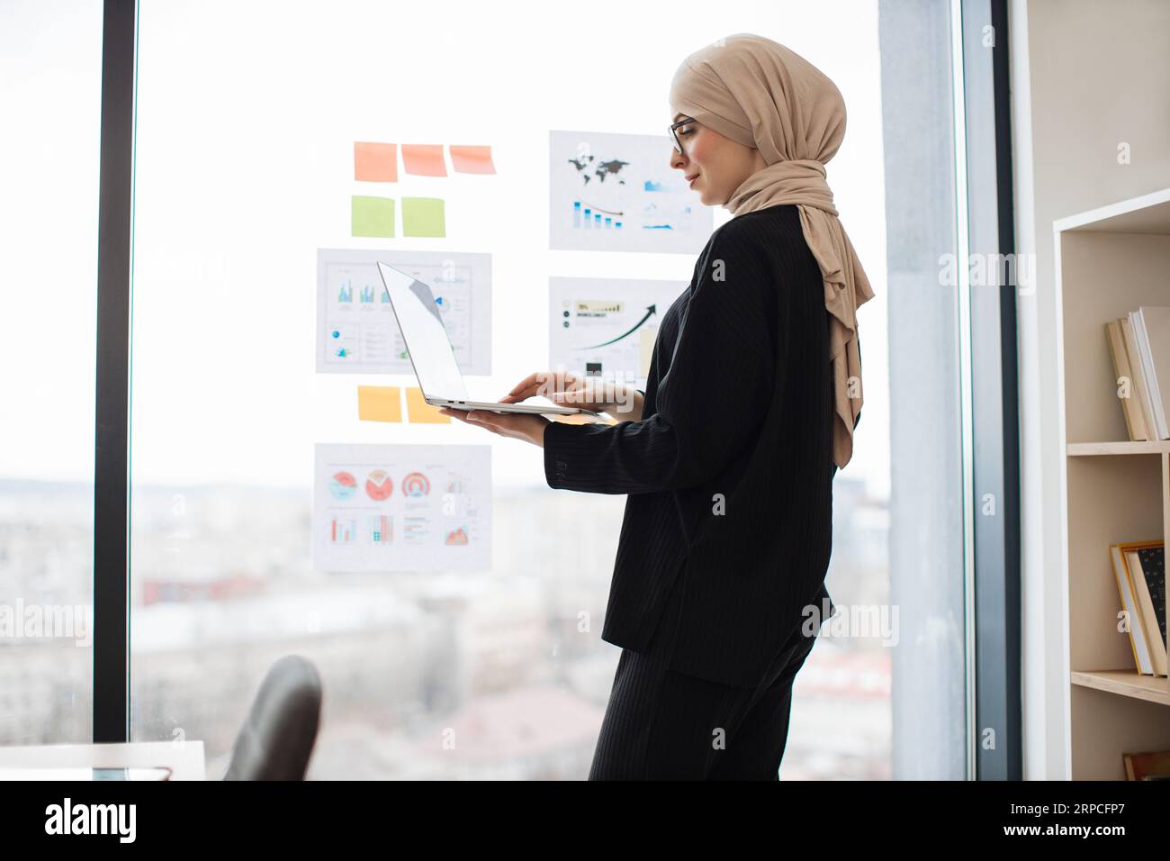 Side view of muslim employee entering words in search engine on laptop ...