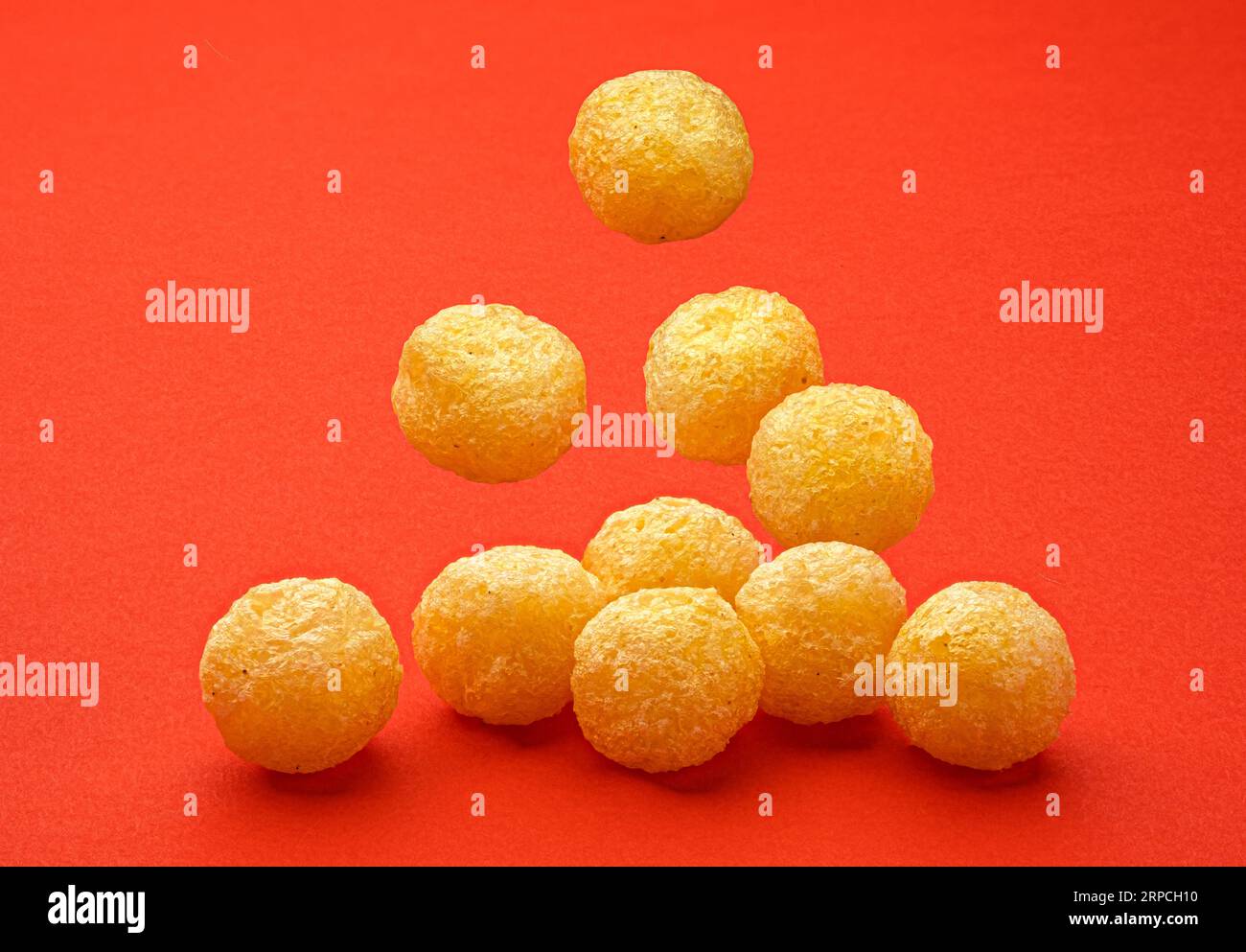 Falling corn balls isolated on red background, full depth of field ...